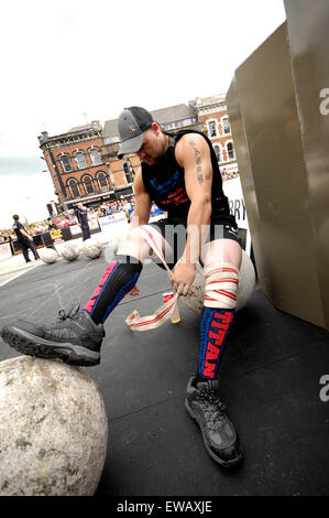 Man competing in a strongman contest lifts a very heavy Atlas Stone ...