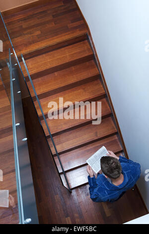 Man reading newspaper on stairs Stock Photo - Alamy