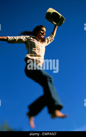 Woman jumping with a cowboy hat Stock Photo - Alamy