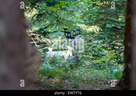 Man player shooting with a paintball gun hiding behind wooden shelter ...