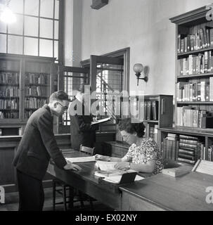 1950s, historical, inside a library, a female libarian showing an ...