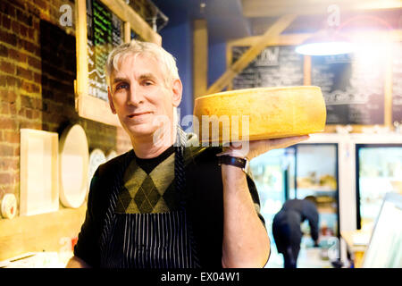 Man holding a wheel of cheese Stock Photo - Alamy