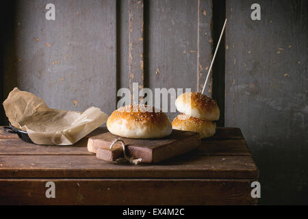 Fresh buns on a wooden board dusted with flour and a rolling pin in the ...