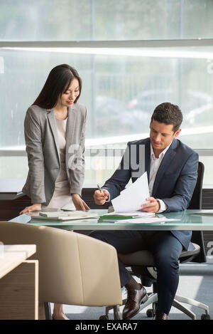 Business executive signing contracts with secretary at desk in office ...