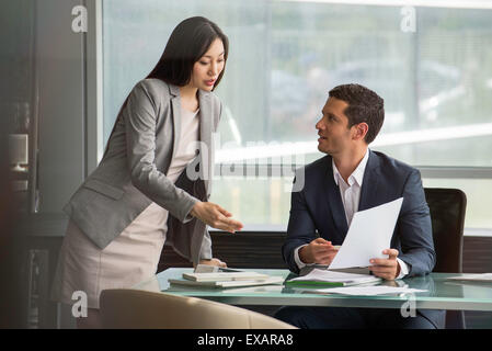 Executive working at office desk with his assistant, they are using a ...