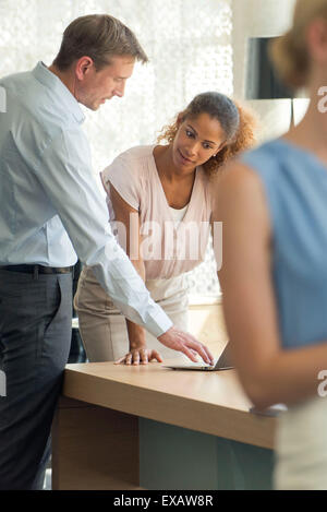 Salesman using tablet computer with colleagues behind him Stock Photo ...