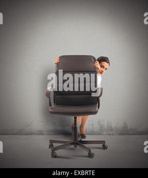 Employee hiding behind chair fearful of boss Stock Photo - Alamy