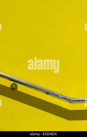 A chrome steel rail against a yellow painted wall Stock Photo - Alamy