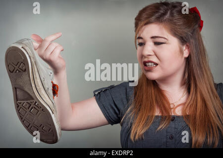 Cute girl holds up smelly stinky sneaker shoe and screams Stock Photo ...