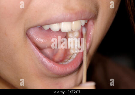 Asian person student swabbing her cheek to obtain cells for DNA ...