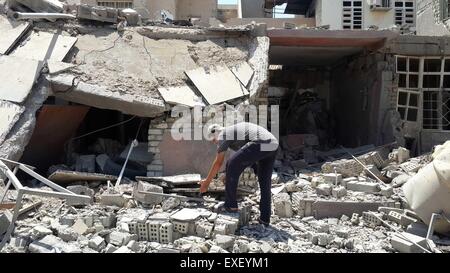 Fallujah, Iraq. 13th July, 2015. A man stands in front of a destroyed ...
