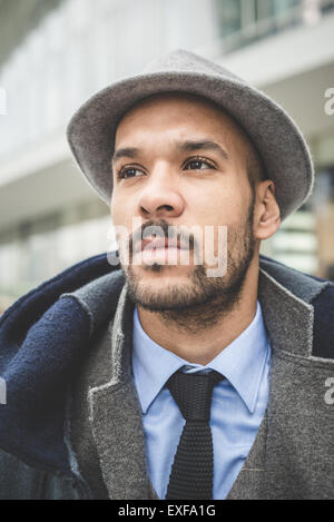 Portrait of businessman waiting outside building, leant on wall Stock ...