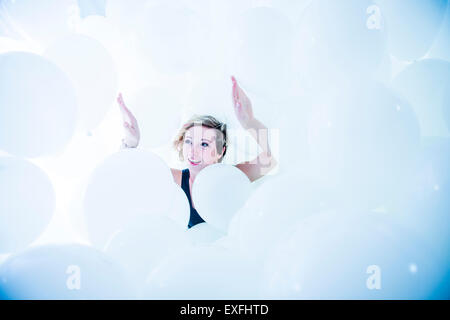 Globophobia: a young woman girl alone in a cloud of hundreds of white ...