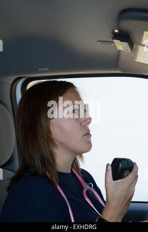Female paramedic EMT using radio in ambulance. Rural volunteer fire ...