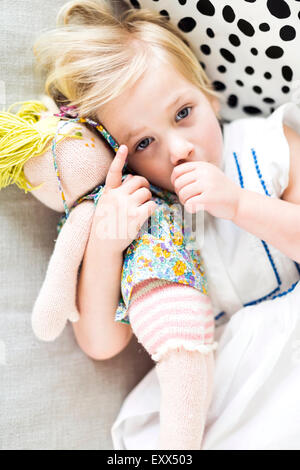 Adorable caucasian girl drawing on notebook sitting on sofa by ...