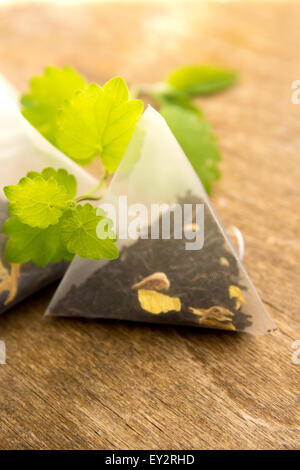 Teabags with fresh green melissa (mint) leaves over rustic wooden ...