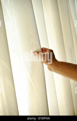 Hand pulling a window curtain for warm daylight to enter the room Stock ...