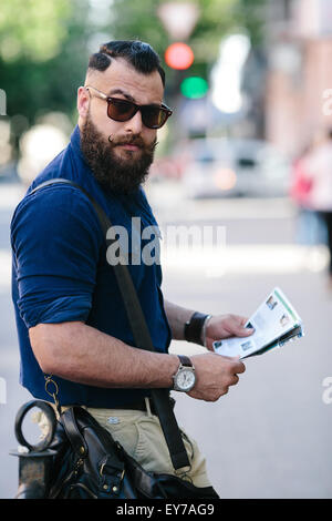 bearded man in stylish sunglasses and trendy beanie hat looking away ...