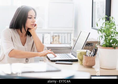 Woman sitting at desk with laptop on blue background Stock Photo - Alamy