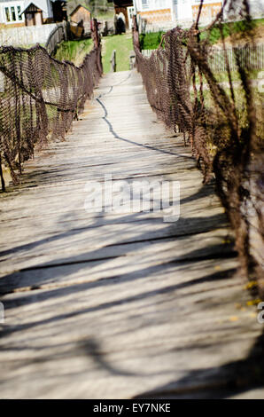 Footbridge connecting a rural village to green fields and a river under ...