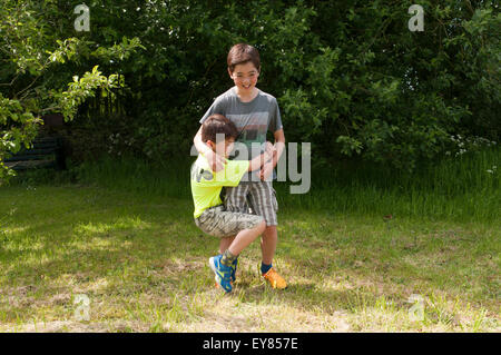 Two boys fighting outdoors. Siblings wrestling on grass in summer park ...