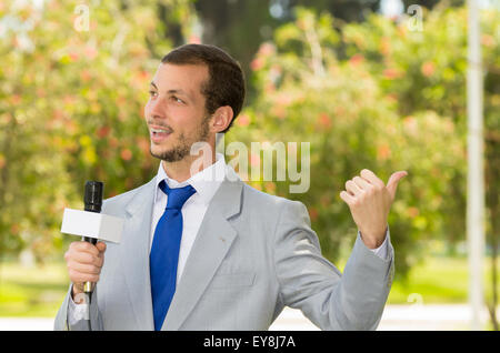 Successful handsome male news reporter wearing light grey suit working ...