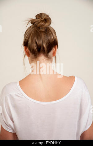A young Caucasian woman turns her back to show the nape of her neck ...