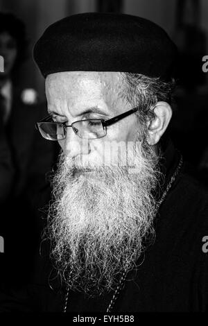 portrait of coptic orthodox christian priest with big cross inside rock ...