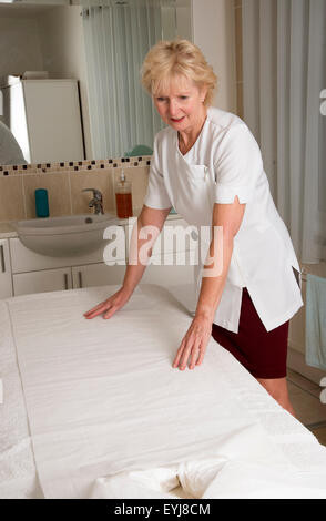 Professional masseuse in white uniform performs relaxing leg massage on ...