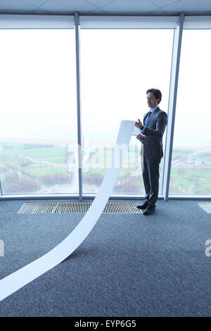 Office worker unrolling long sheet of paper Stock Photo - Alamy