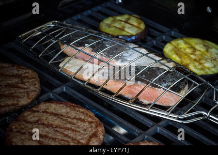 Hamburger slices, salmon steak and eggplant on grill rack, soft focus ...