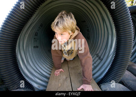 Boy crawling through tunnel in playground Stock Photo - Alamy