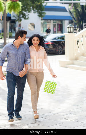 Young hispanic couple holding shopping bags at retail shop angry and ...