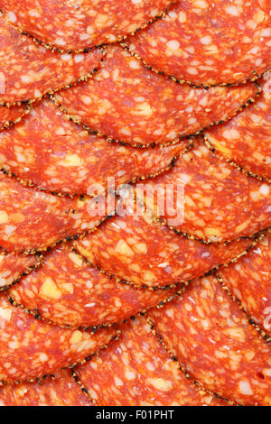Thin slices of black pepper-coated salami speckled with pieces of Comte ...