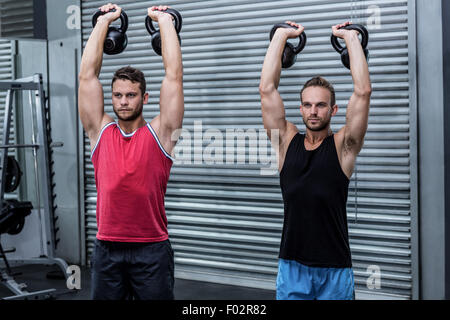 Muscular men lifting a kettle bell Stock Photo - Alamy