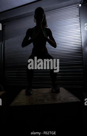 Sporty woman doing jumping squats exercises on stairs in park ...