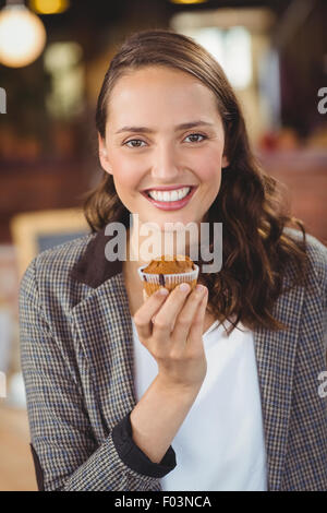 Smiling young woman showing muffin Stock Photo - Alamy