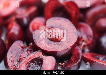 fresh red cherries cut into halves on white cutting board kitchen still ...