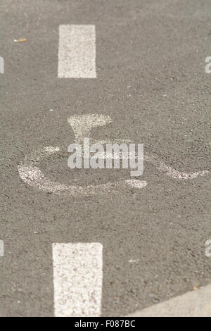 Disabled parking bay with wheelchair user icon, painted yellow on red ...