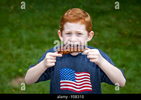 Boy eating a BBQ rib outside getting messy Stock Photo - Alamy