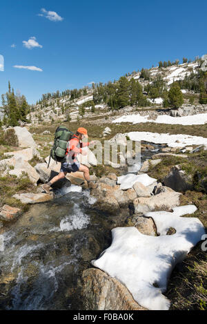 Woman jumping across stream Stock Photo - Alamy