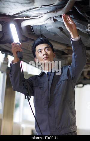 Man working on car by flashlight. Mechanic fixing auto, repair at night ...