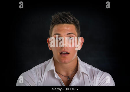 Surprised, unsure handsome young man looking down at something in front ...
