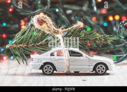 Toy car with small Christmas tree, gift and ball on color background ...
