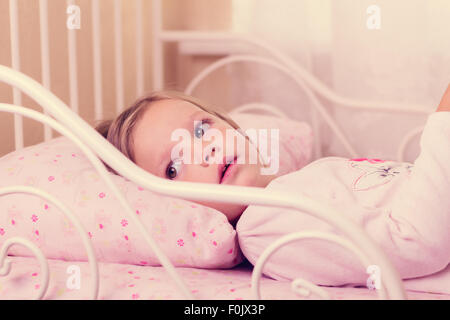 Cute little girl falls asleep on a pink sofa. Child embraces a ...