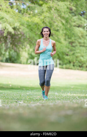 Happy woman running through trees in forest Stock Photo - Alamy