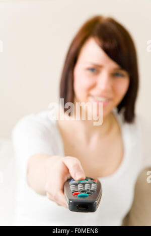 Woman in the living room changing the TV channel with the remote ...