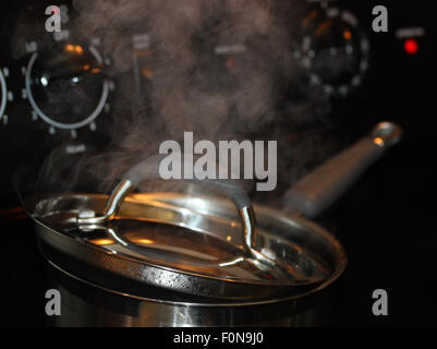 Cooking pot or saucepan with steam coming out as water boils on the ...