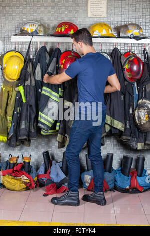 Firefighter, uniform and clothing hanging on wall rack at station for ...