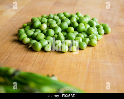 A pile of fresh green peas, some shelled and some still in their pods ...